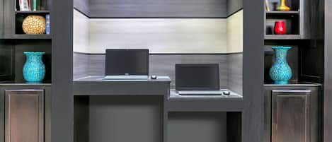 Um espaço de escritório moderno com duas mesas, cada uma com um laptop e um rato. Estantes com vasos decorativos e livros de cada lado.
