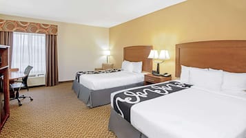 Quarto de hotel com duas camas, uma escrivaninha e uma cadeira.