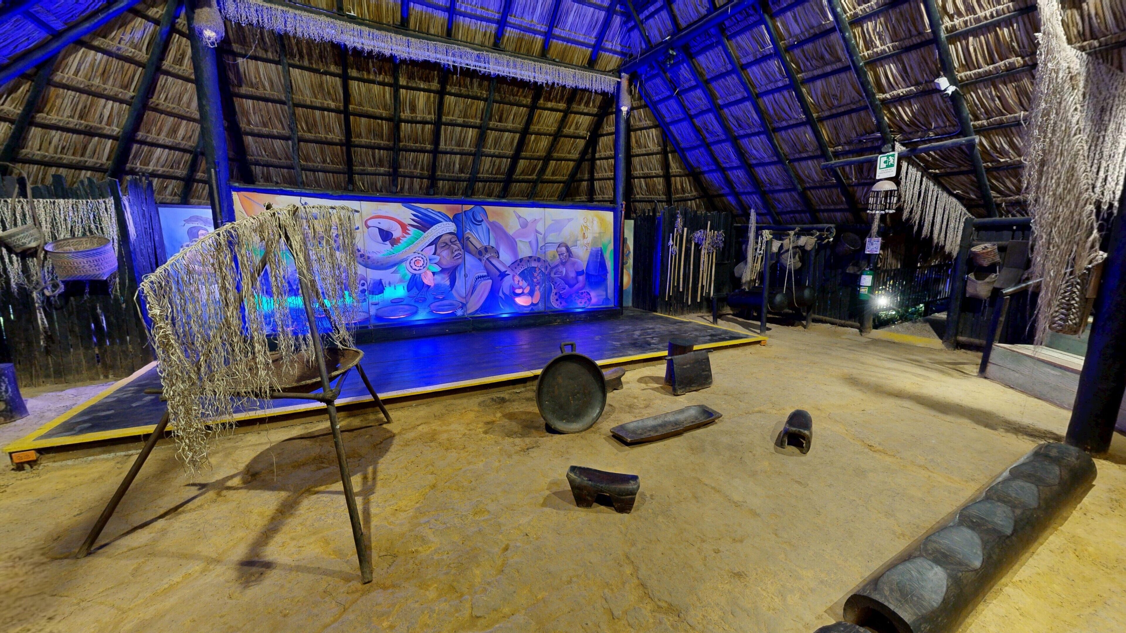 Um interior com palco, cadeira suspensa e diversos objetos no chão.