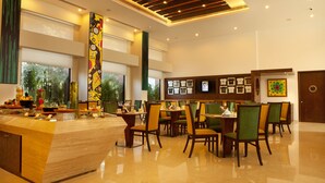 Um saguão de hotel moderno com balcão de recepção, área de refeições e grandes janelas.