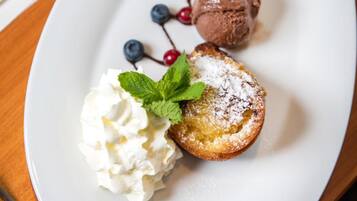 Um prato de sobremesa com chantilly, um pastel com fruta e uma bola de sorvete.