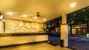 Uma área de recepção com um grande mural na parede, um balcão de atendimento e uma escadaria que leva aos andares superiores.
