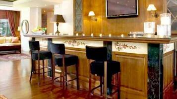 Uma área de bar com banquetas de madeira e uma televisão fixada acima.