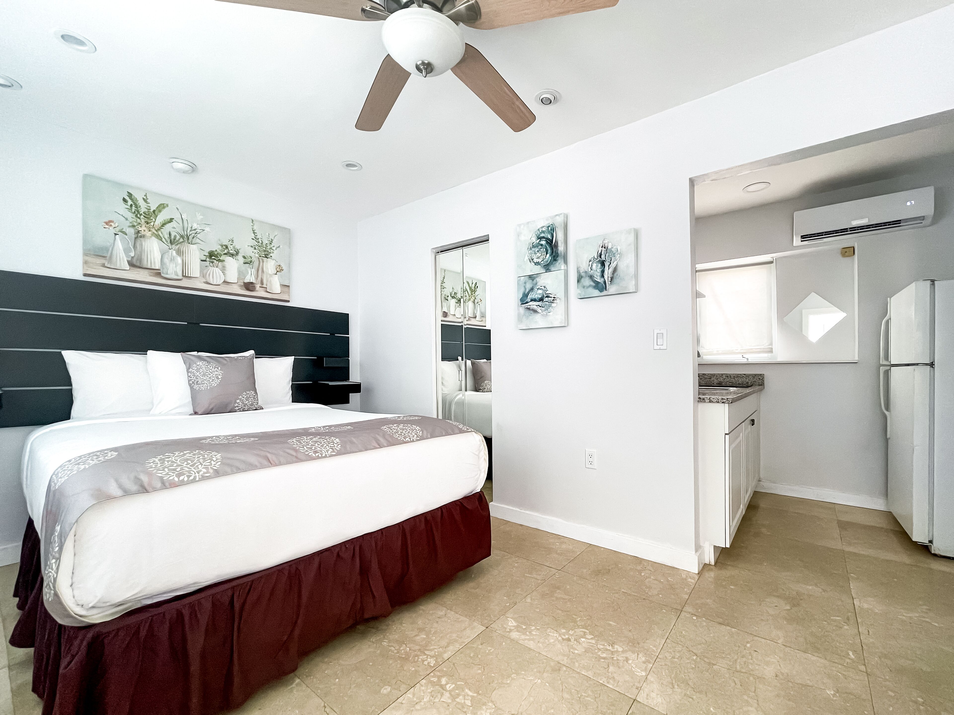 Quarto com cama, ventilador de teto e obras de arte nas paredes.