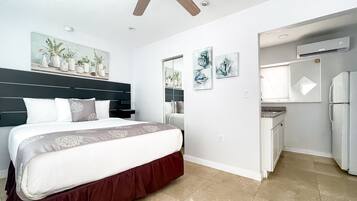 Quarto com cama, ventilador de teto e obras de arte nas paredes.