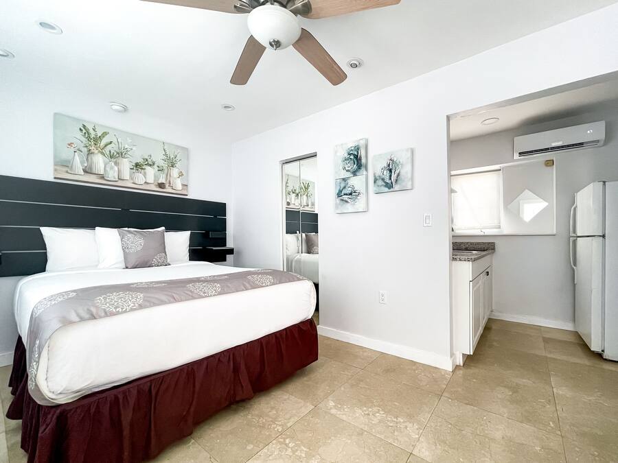 Quarto com cama, ventilador de teto e obras de arte nas paredes.