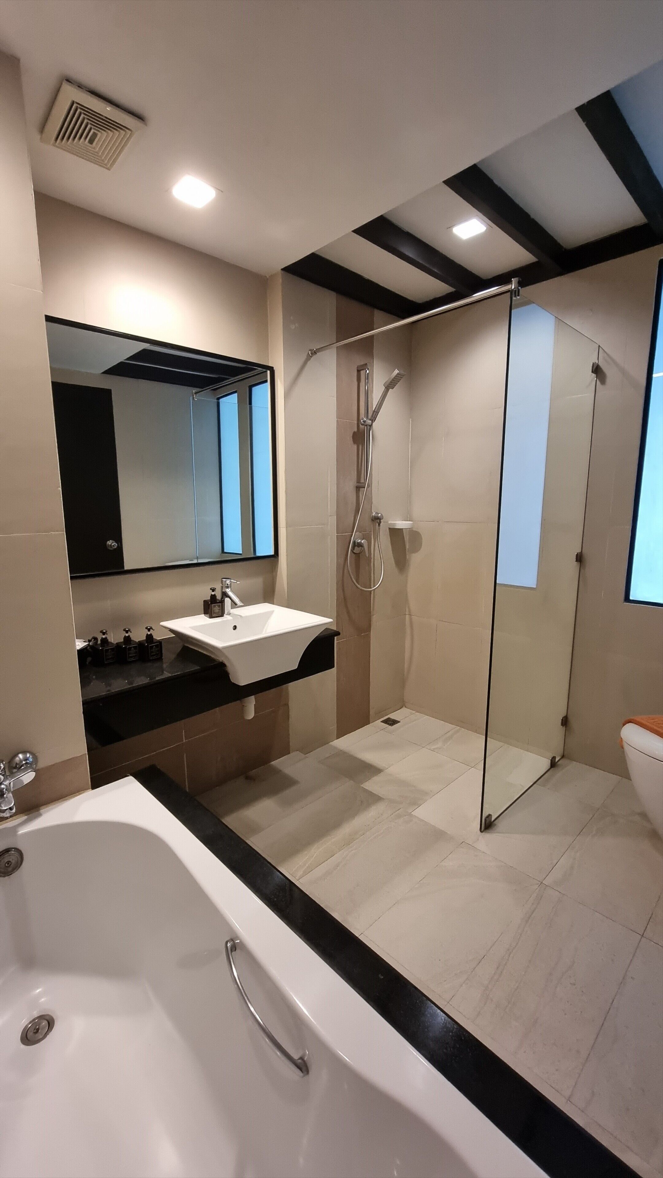 Uma casa de banho moderna com banheira, chuveiro com cabine de vidro e um espelho grande.