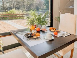 Uma mesa de jantar com itens de café da manhã, uma planta e vista para o exterior.