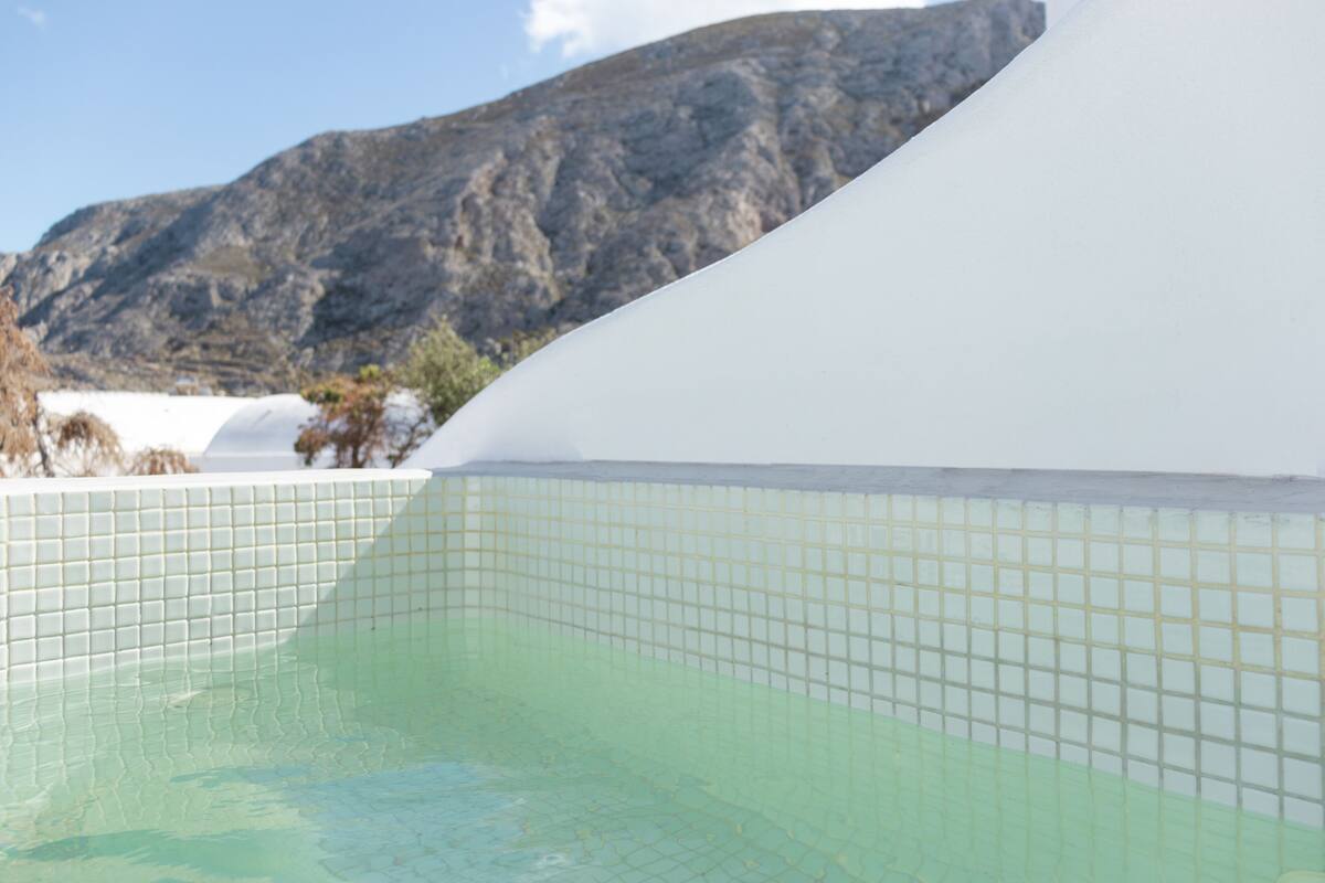 Uma piscina com paredes azulejadas e montanhas ao fundo.