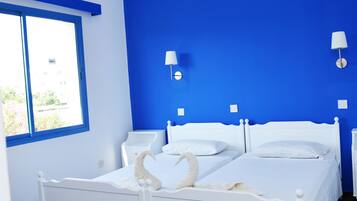 Quarto com cama branca, paredes azuis e uma janela.