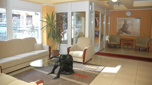 Uma sala de estar com sofá, poltronas, mesa de centro de vidro e uma estátua.