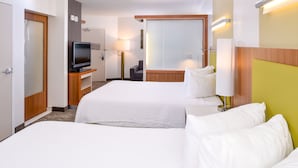 Quarto de hotel com duas camas, televisão, escrivaninha e uma cadeira.