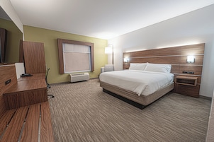 Quarto de hotel com cama, mesas de cabeceira, escrivaninha, cadeira, janela com persianas e luminária na parede.
