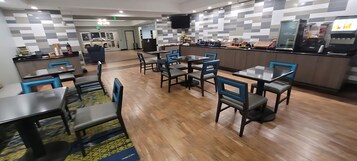 Restaurante moderno com piso de madeira, cadeiras azuis e mesas.