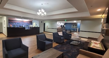 Um hall de hotel com balcão de recepção, área de estar e espaço para refeições.
