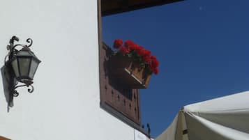 Um edifício com fachada branca, um lampião de metal preto e uma cesta de flores com flores vermelhas.