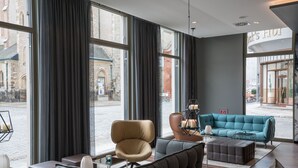 Uma sala de estar moderna com grandes janelas, um sofá, poltronas e uma mesa de centro.