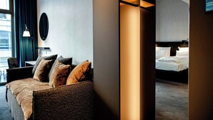 Quarto de hotel moderno com sofá, escrivaninha e cama.