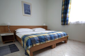 Um quarto com cama, mesa de cabeceira e um quadro na parede.