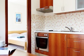 Uma cozinha compacta com armários de madeira, forno de aço inoxidável e painel de azulejos.