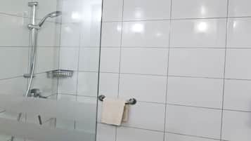 Casa de banho moderna com chuveiro de vidro, paredes revestidas de azulejos brancos e porta-toalhas à vista.