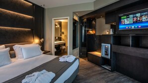 Quarto de hotel moderno com cama grande, televisão na parede e closet espaçoso.
