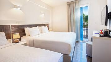 Quarto de hotel com duas camas, escrivaninha, televisão e vista para o exterior.