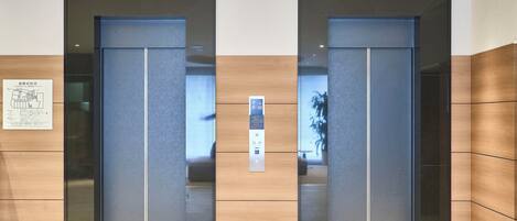 Um elevador moderno com painel de controle, painéis de madeira nas paredes e piso com azulejo claro.