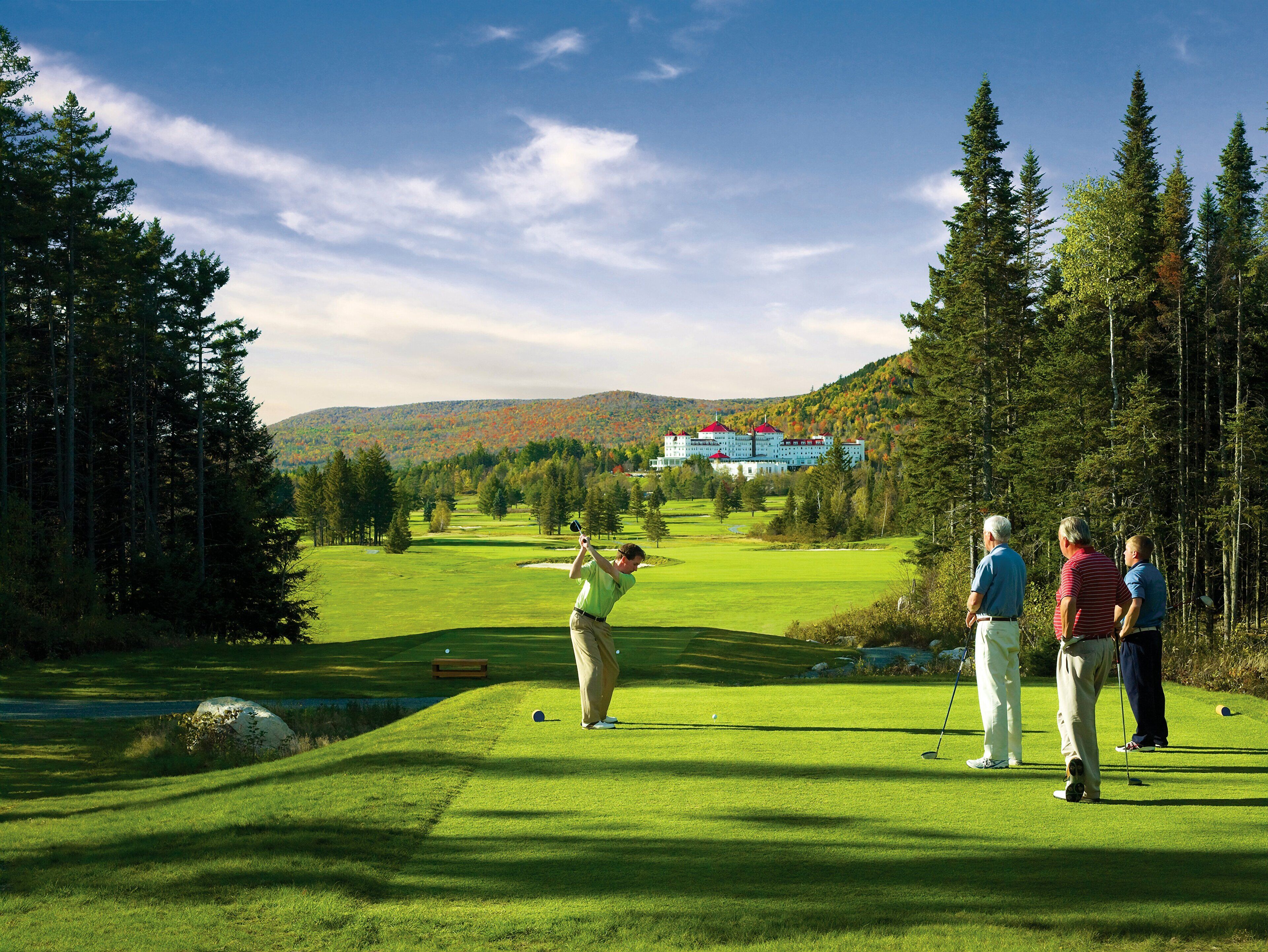 Um campo de golfe com um clube de campo ao fundo.
