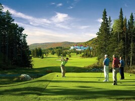 Um campo de golfe com um clube de campo ao fundo.
