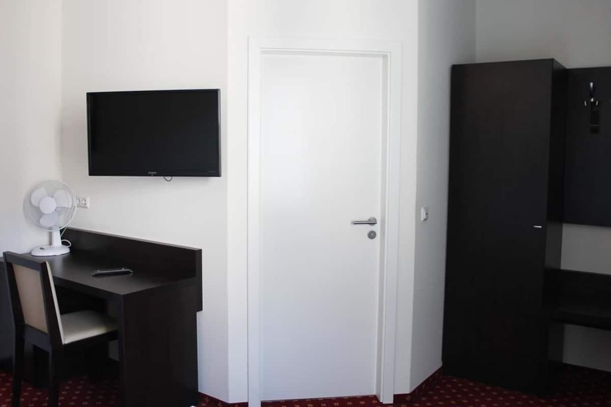 Quarto com escrivaninha, cadeira, porta branca e armário preto.