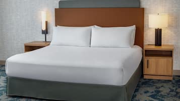 Quarto de hotel com uma cama grande, duas mesas de cabeceira e um abajur.