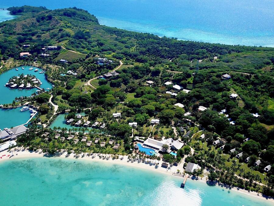 Vista aérea de um resort com vários edifícios, uma praia e um porto de iates.