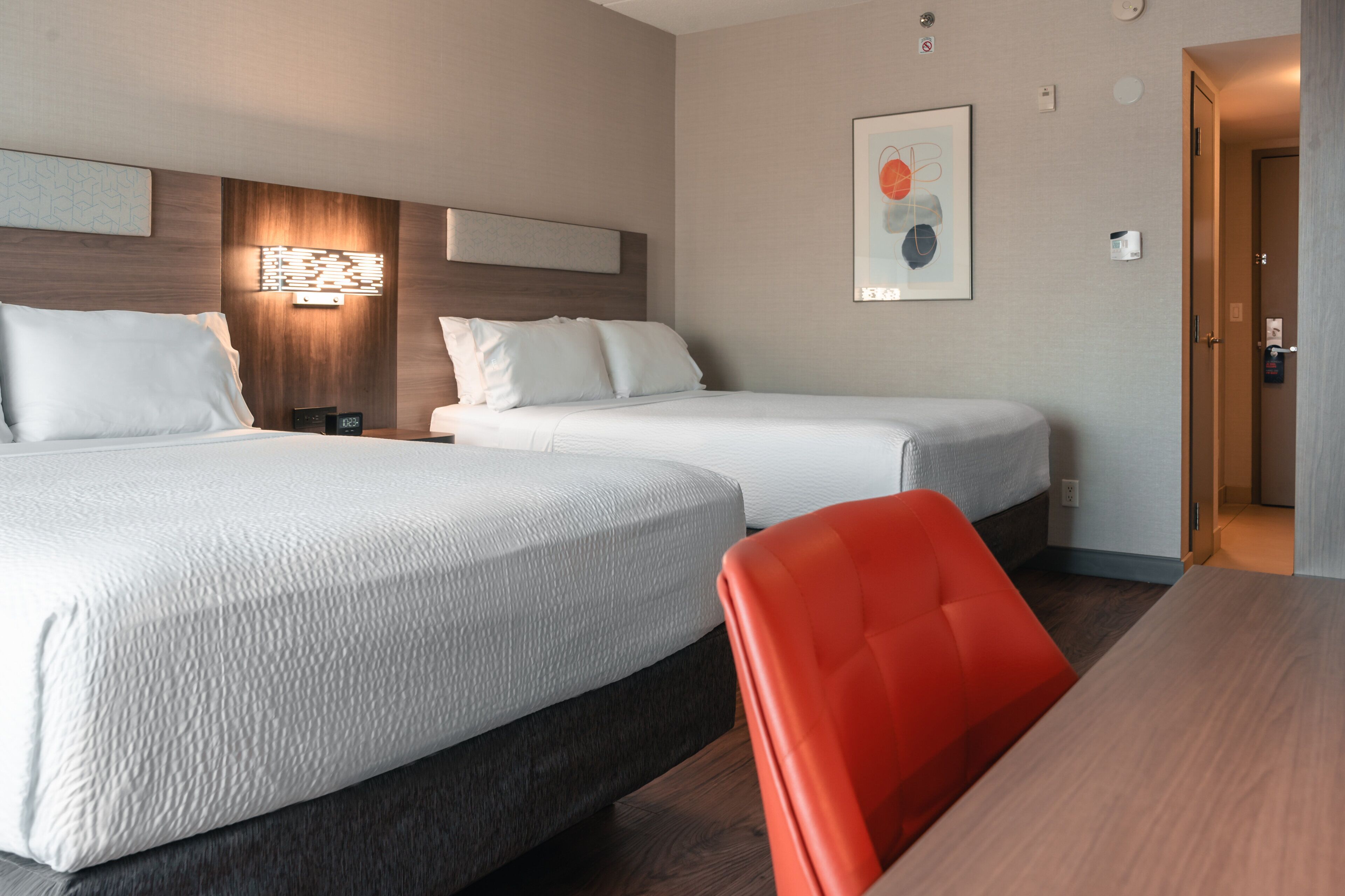 Quarto de hotel com duas camas, uma escrivaninha e uma cadeira.