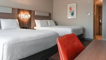 Quarto de hotel com duas camas, uma escrivaninha e uma cadeira.