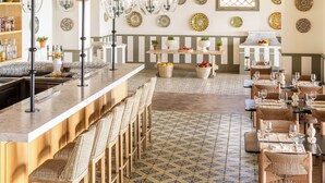 Um restaurante com candelabros de vime, azulejos estampados e um bar com banquetes.