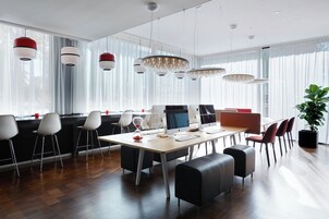 Uma sala de conferências moderna com uma mesa comprida, várias cadeiras e diversos monitores de computador.