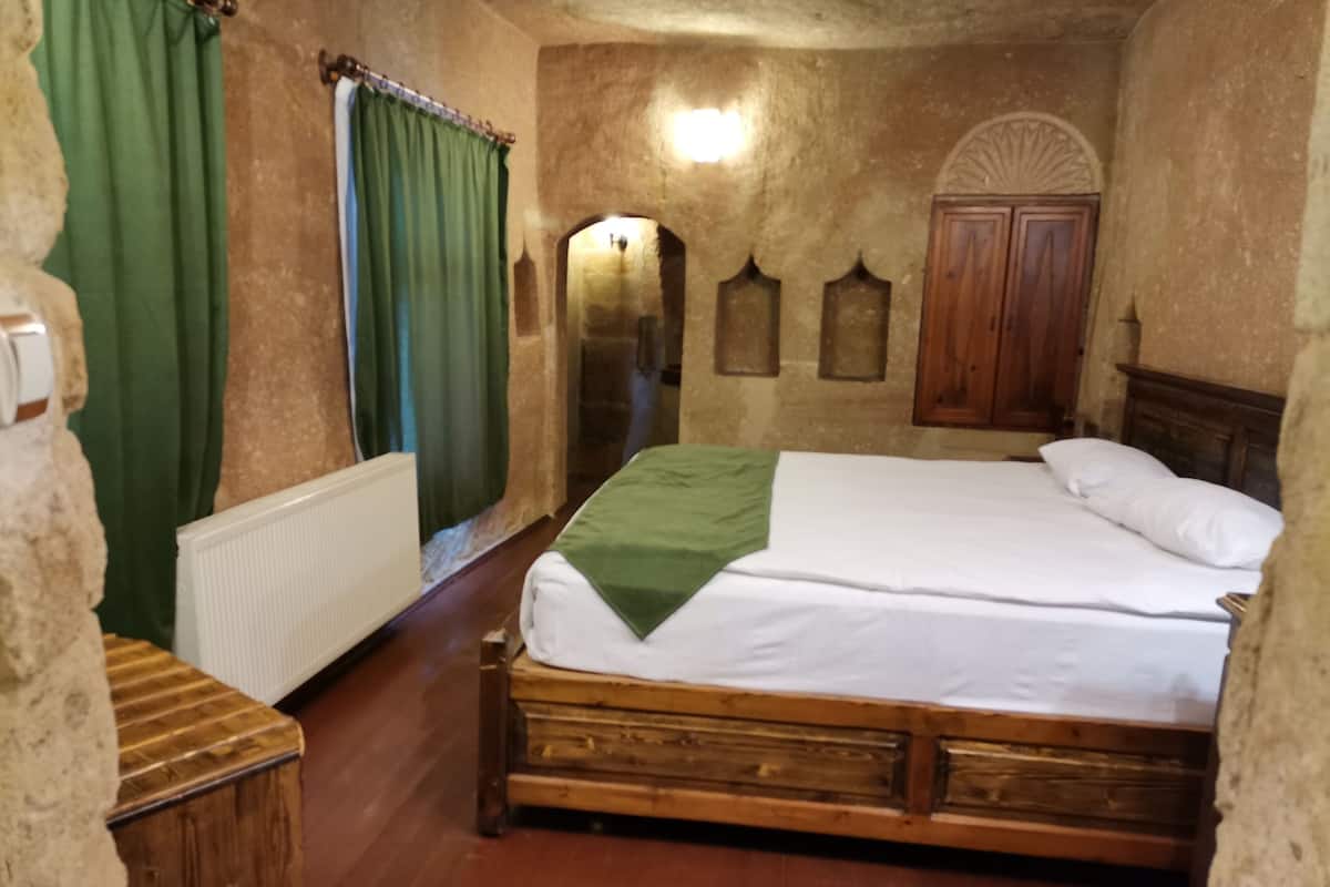 Quarto com cama de madeira, cortinas verdes, radiador e armário de madeira.