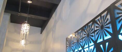 Teto com lustres de cristal pendurados e parede com padrão de luz geométrico.