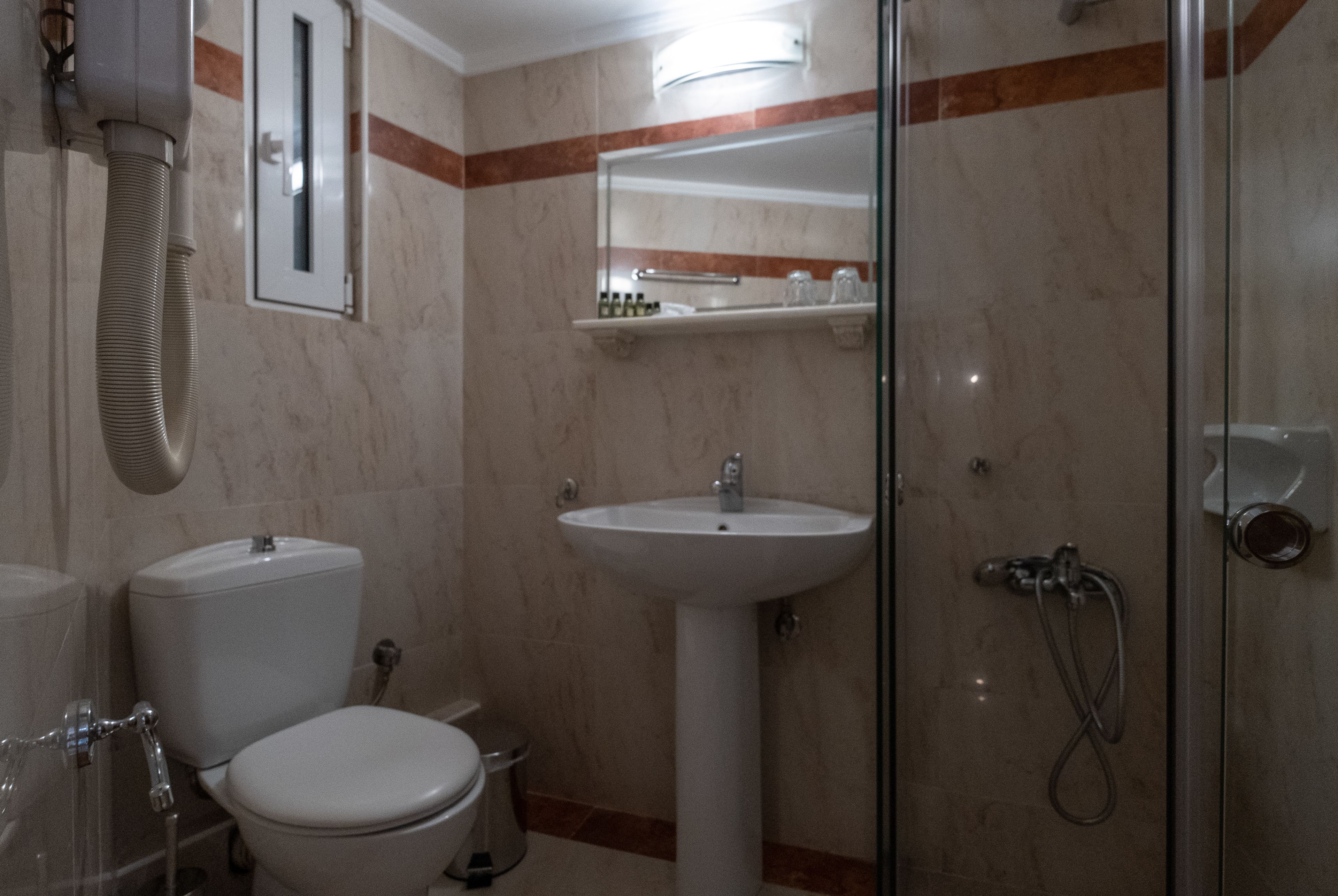 Casa de banho com sanita, lavatório e chuveiro.