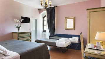 Quarto de hotel com duas camas, televisão, escrivaninha com luminária e janela com cortinas.