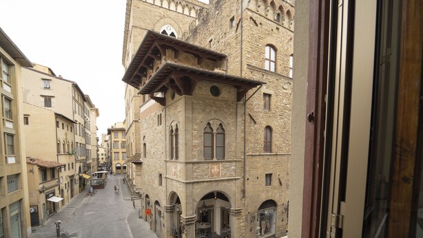 Um edifício histórico de pedra com janelas em arco e uma torre com relógio.