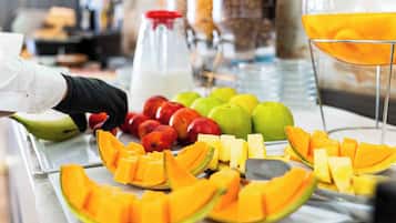 Uma tábua de frutas com diversas frutas e um copo de suco de laranja.