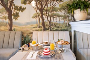Uma área de refeições com uma mesa posta para o café da manhã, incluindo doces, um bolo e suco de laranja.