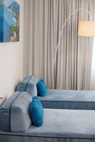 Quarto moderno com dois sofás cinza, uma almofada estampada em azul e um abajur.