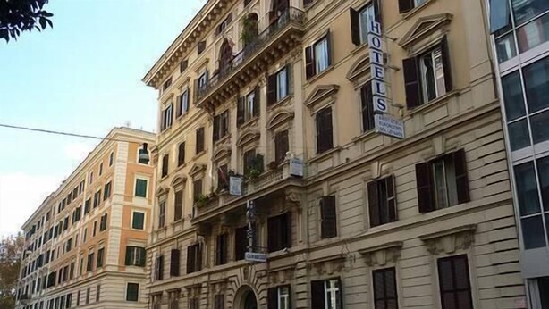 Um hotel de vários andares com estilo arquitetônico clássico, com janelas em arco e sacadas.