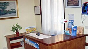 Um balcão de atendimento de madeira com uma placa, um vaso de planta e um quadro na parede.