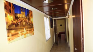 Um corredor com um quadro grande emoldurado de um edifício, uma porta e um chão em mosaico.