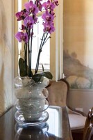 Um vaso com orquídeas roxas sobre uma mesa.