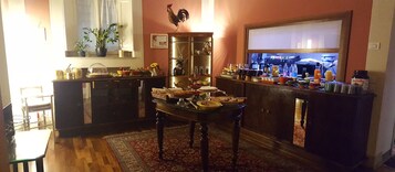 Uma cozinha com uma mesa de jantar, um armário com portas de vidro e uma janela com cortinas.